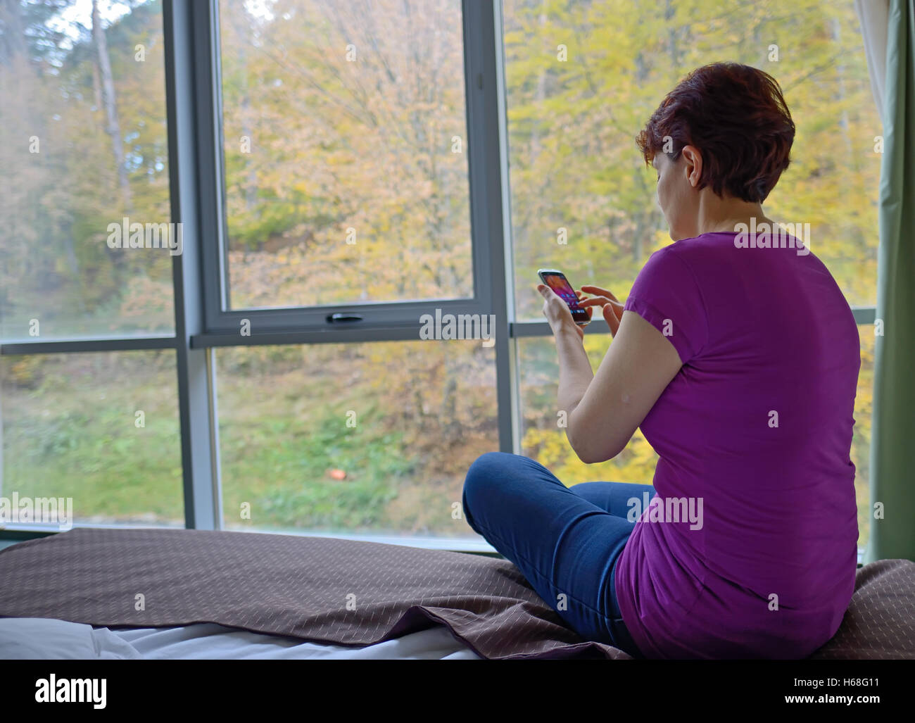 Woman using her smartphone on bed at hotel room Stock Photo - Alamy