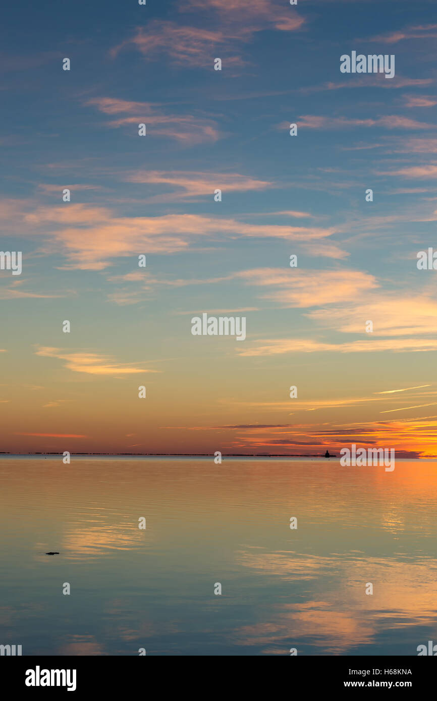 Reflections of a sunset in still ocean water Stock Photo - Alamy