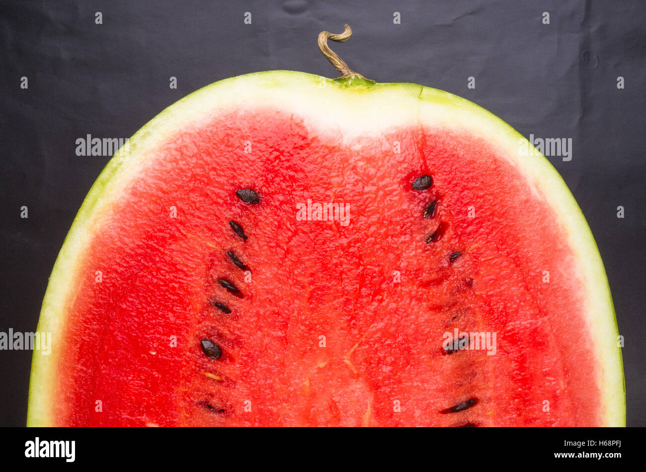 half of ripe watermelon on a black background Stock Photo - Alamy