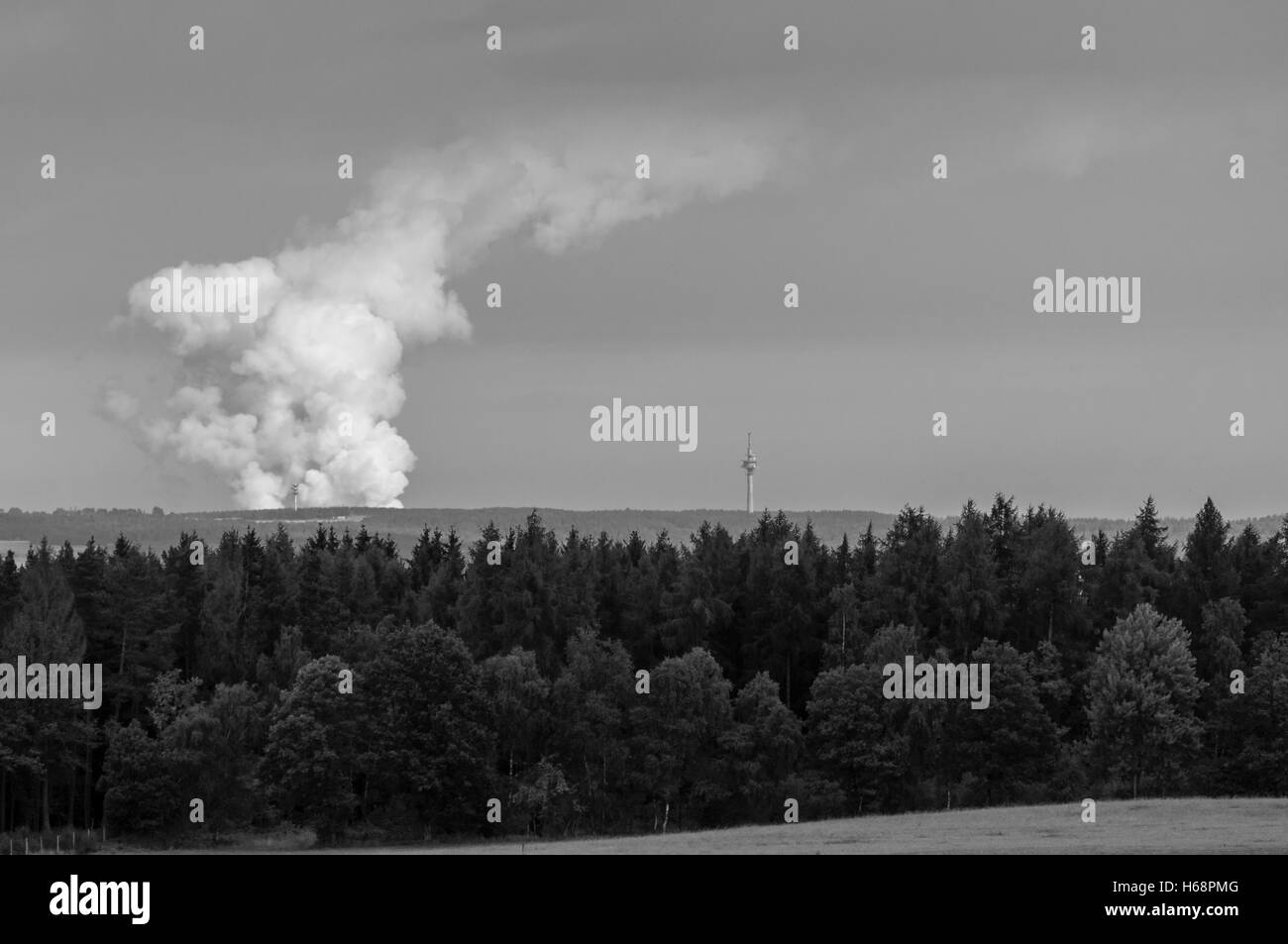 Forest landscape with steam or vapor rising from an industrial complex ...