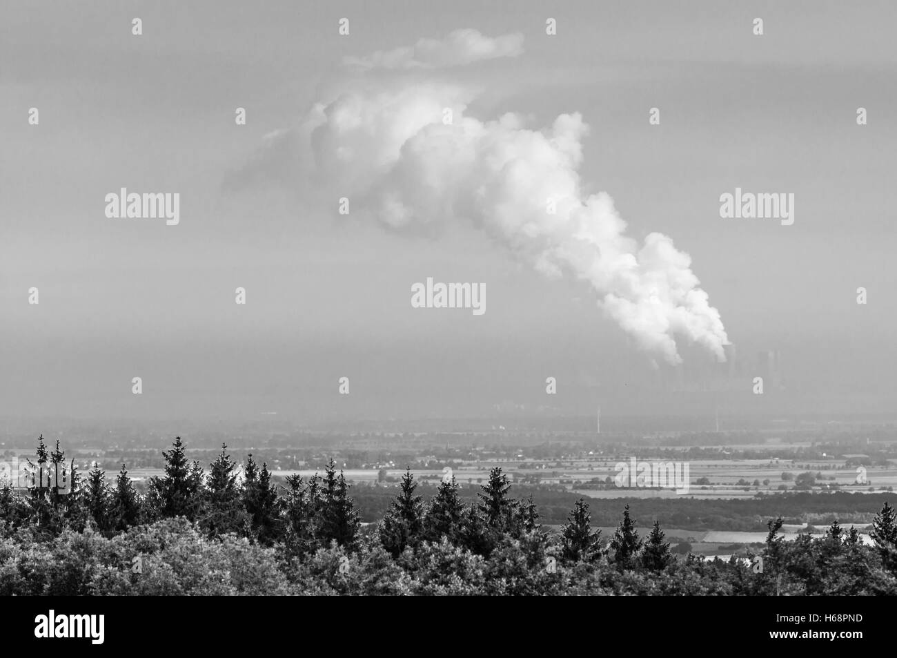 Forest landscape with steam or vapor rising from an industrial complex ...
