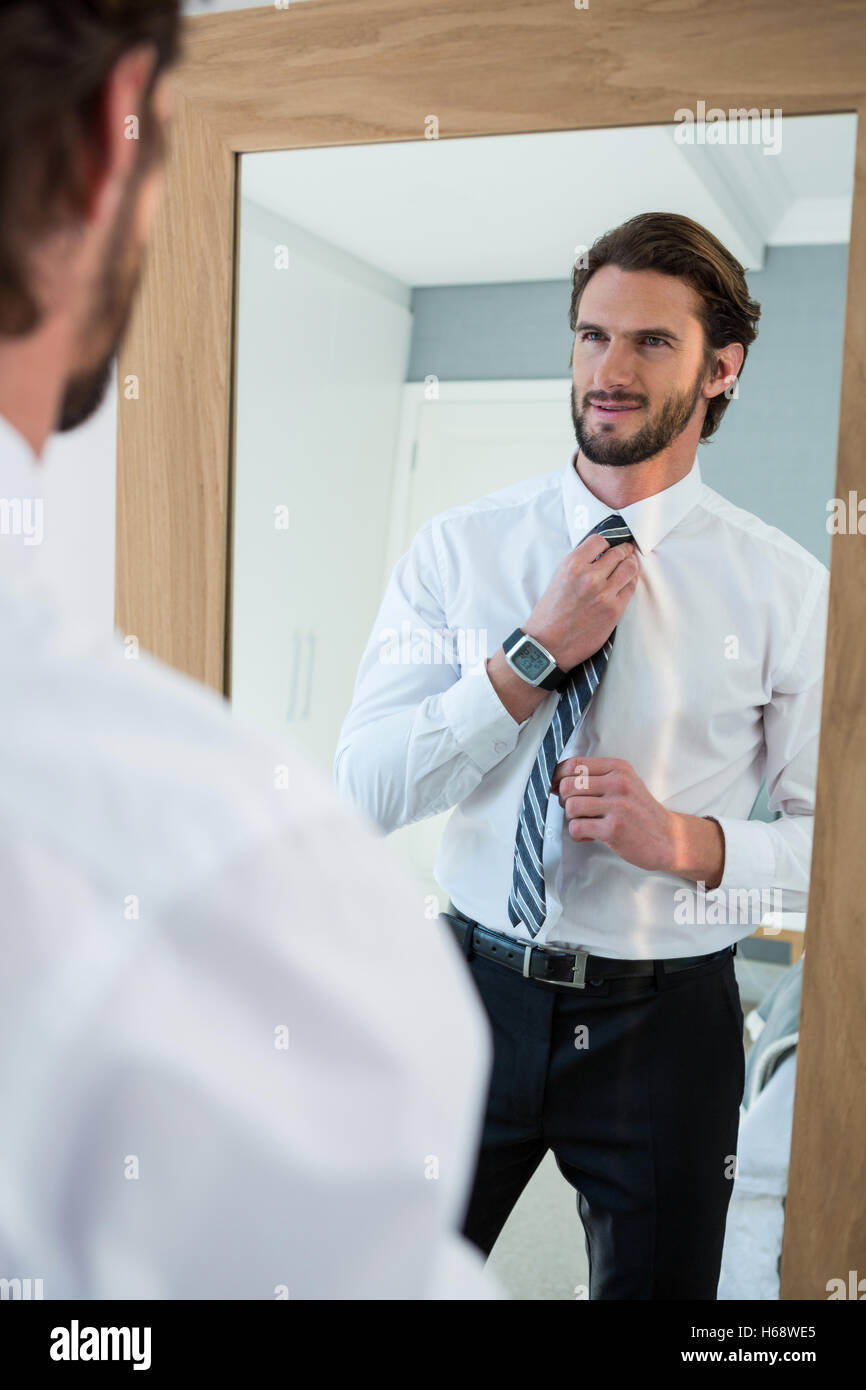 Man getting dressed in bedroom while looking at mirror Stock Photo - Alamy