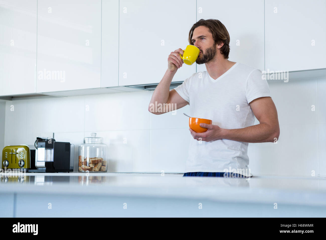 Man drinking coffee while having breakfast in kitchen Stock Photo - Alamy
