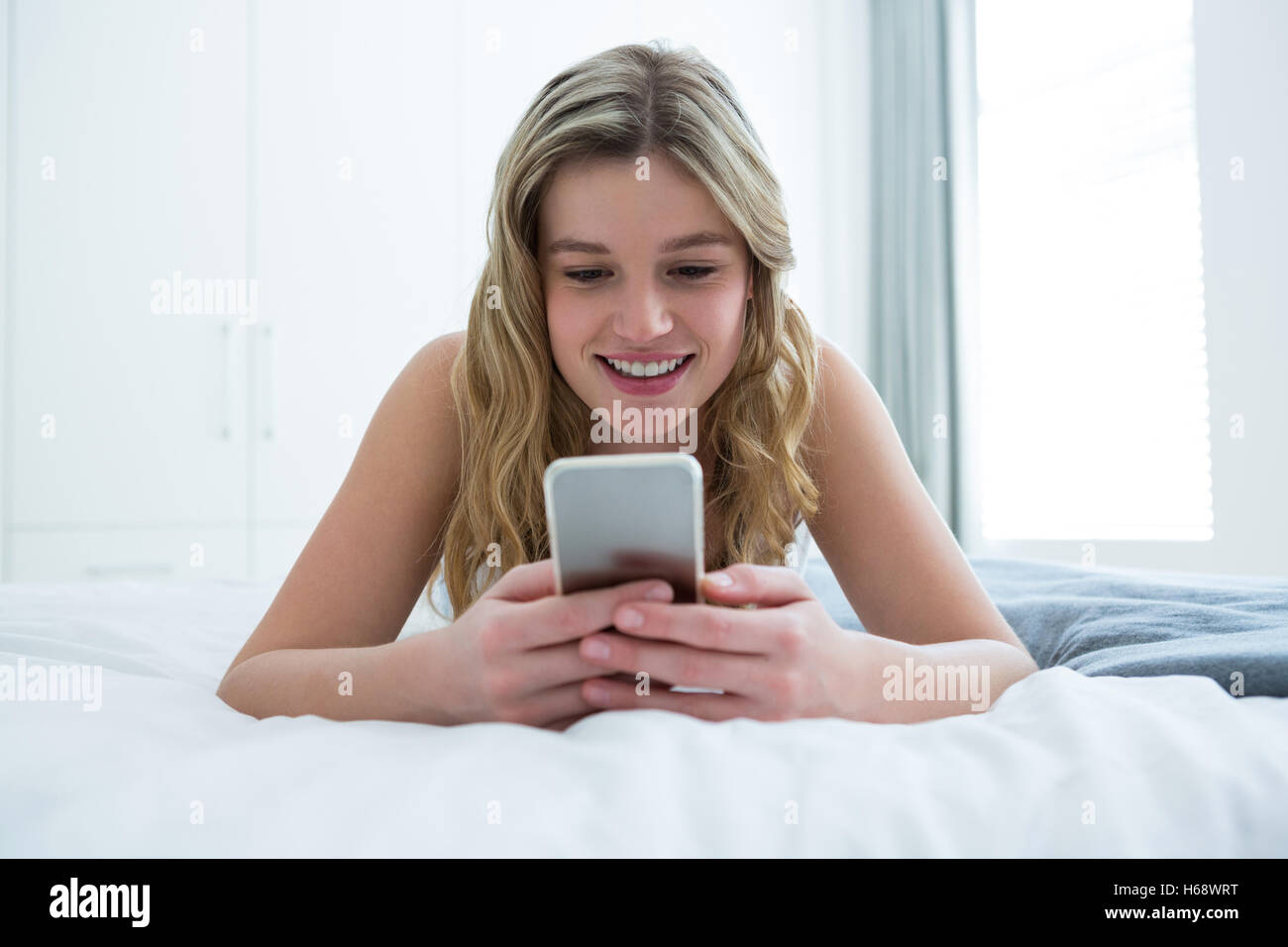 Woman lying on bed and using mobile phone on bed Stock Photo - Alamy