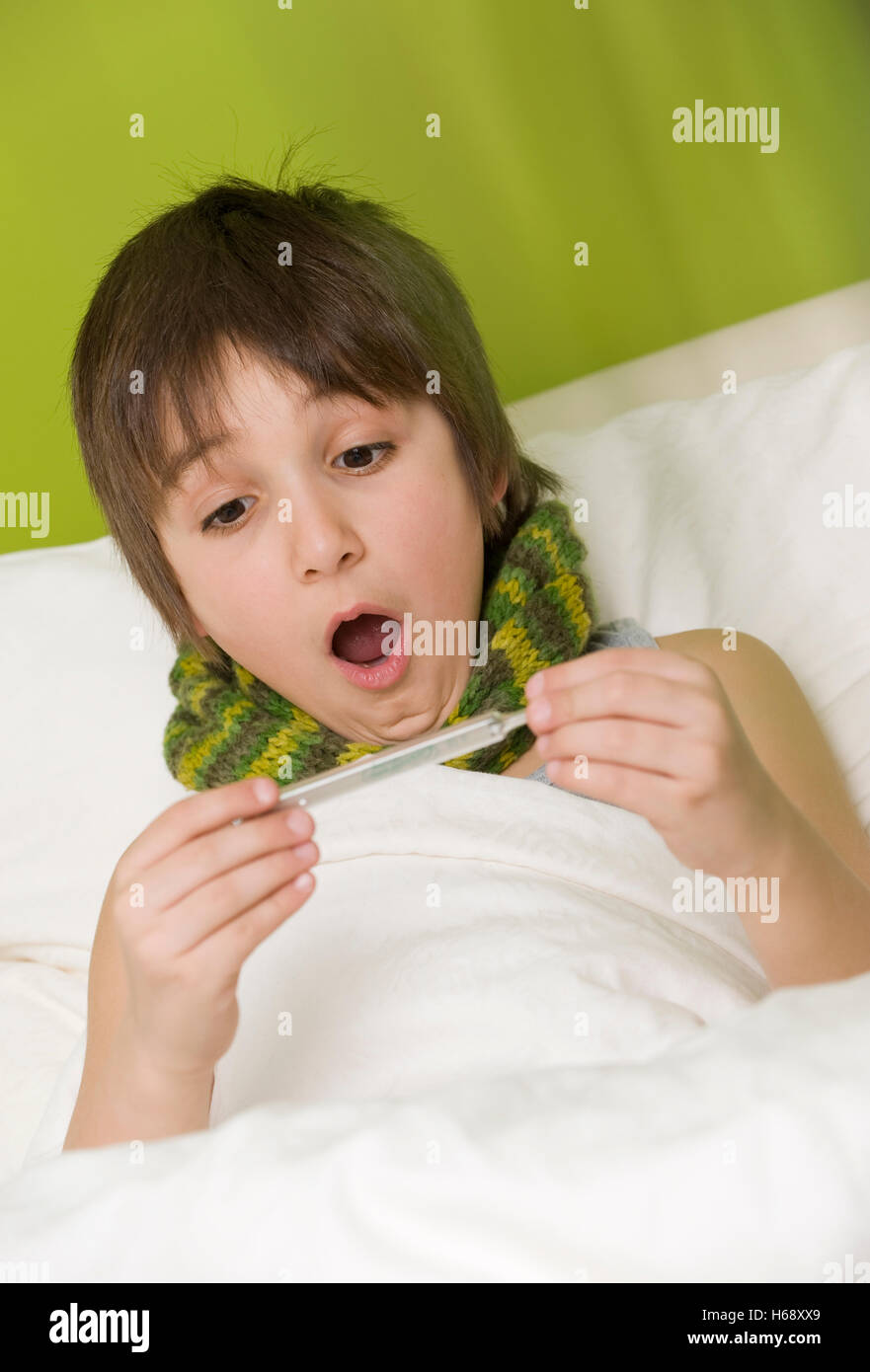 Sick boy with fever in bed, thermometer Stock Photo - Alamy