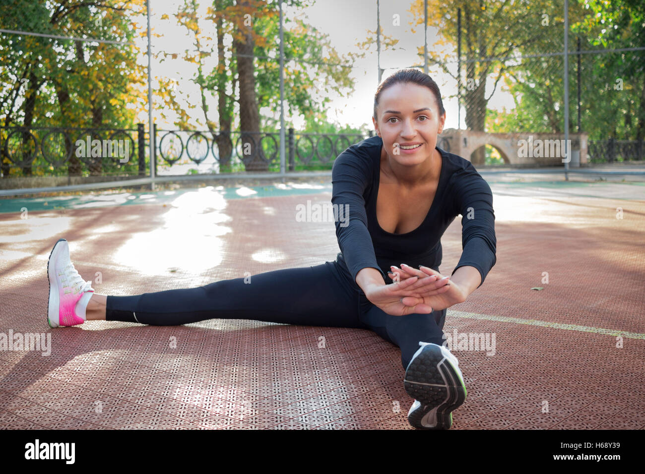 Young pretty fitness woman does stretching exercises during sport ...