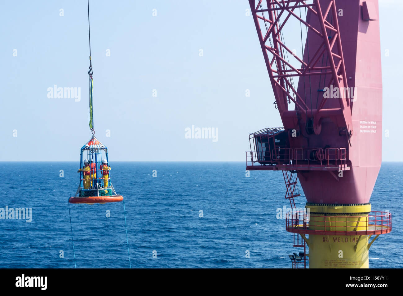 Offshore worker being transferred to boat using personnel basket ...