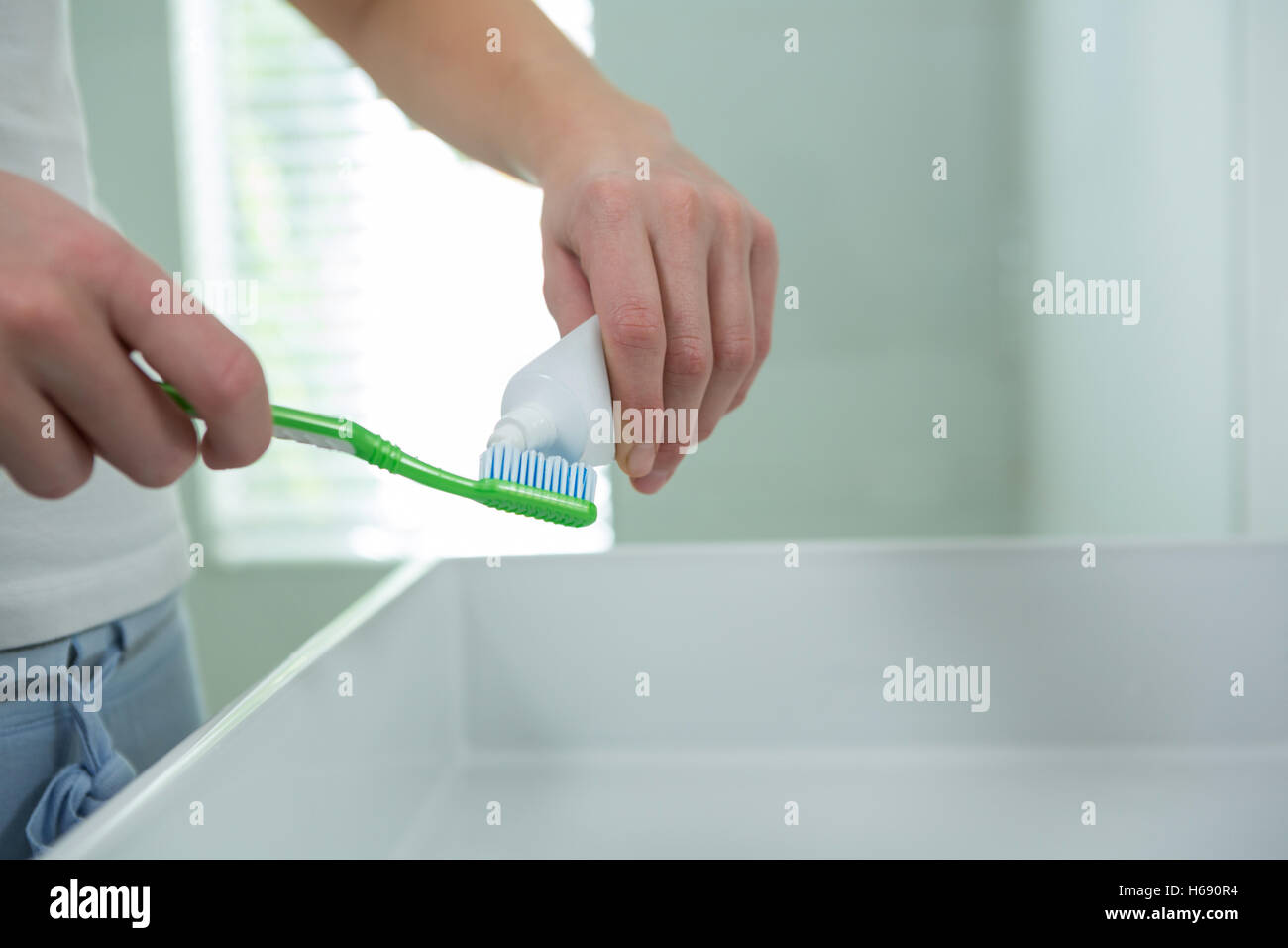 Woman putting toothpaste on brush in bathroom Stock Photo - Alamy