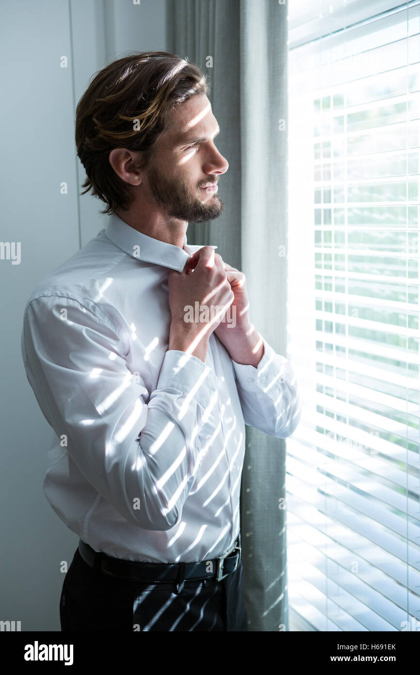 Man getting dressed while looking through window blinds Stock Photo - Alamy