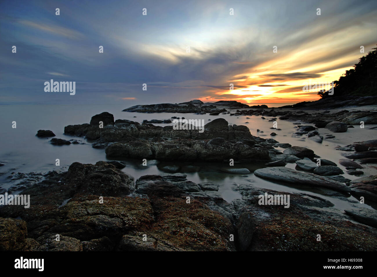 rocks in calm sea with beautiful sunrise background Stock Photo - Alamy