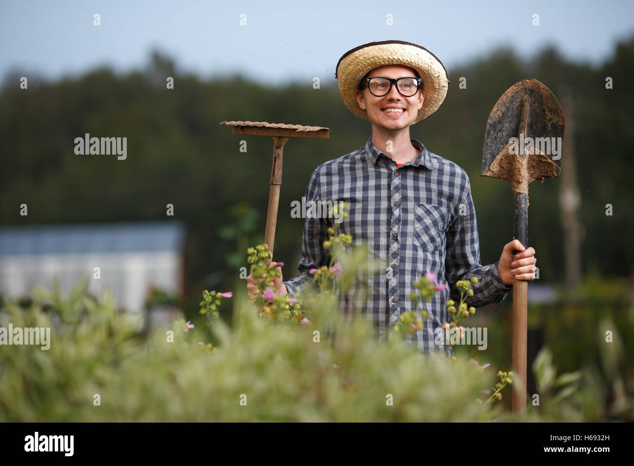 Happy male farmer with shovel and rake on the nature Stock Photo - Alamy