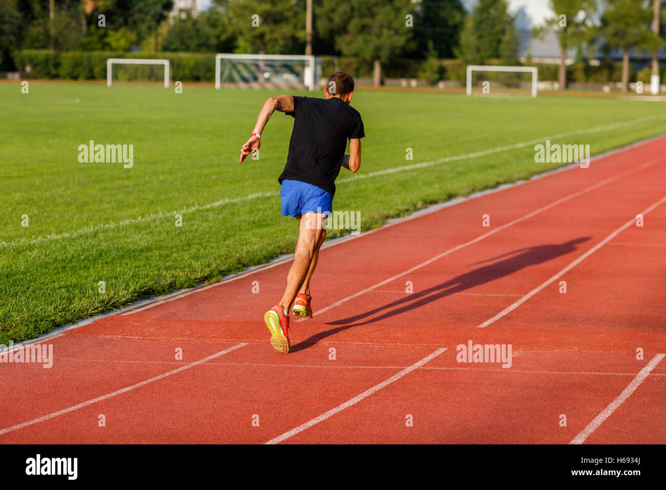 Athletic man in sports clothes running on special street track Stock ...