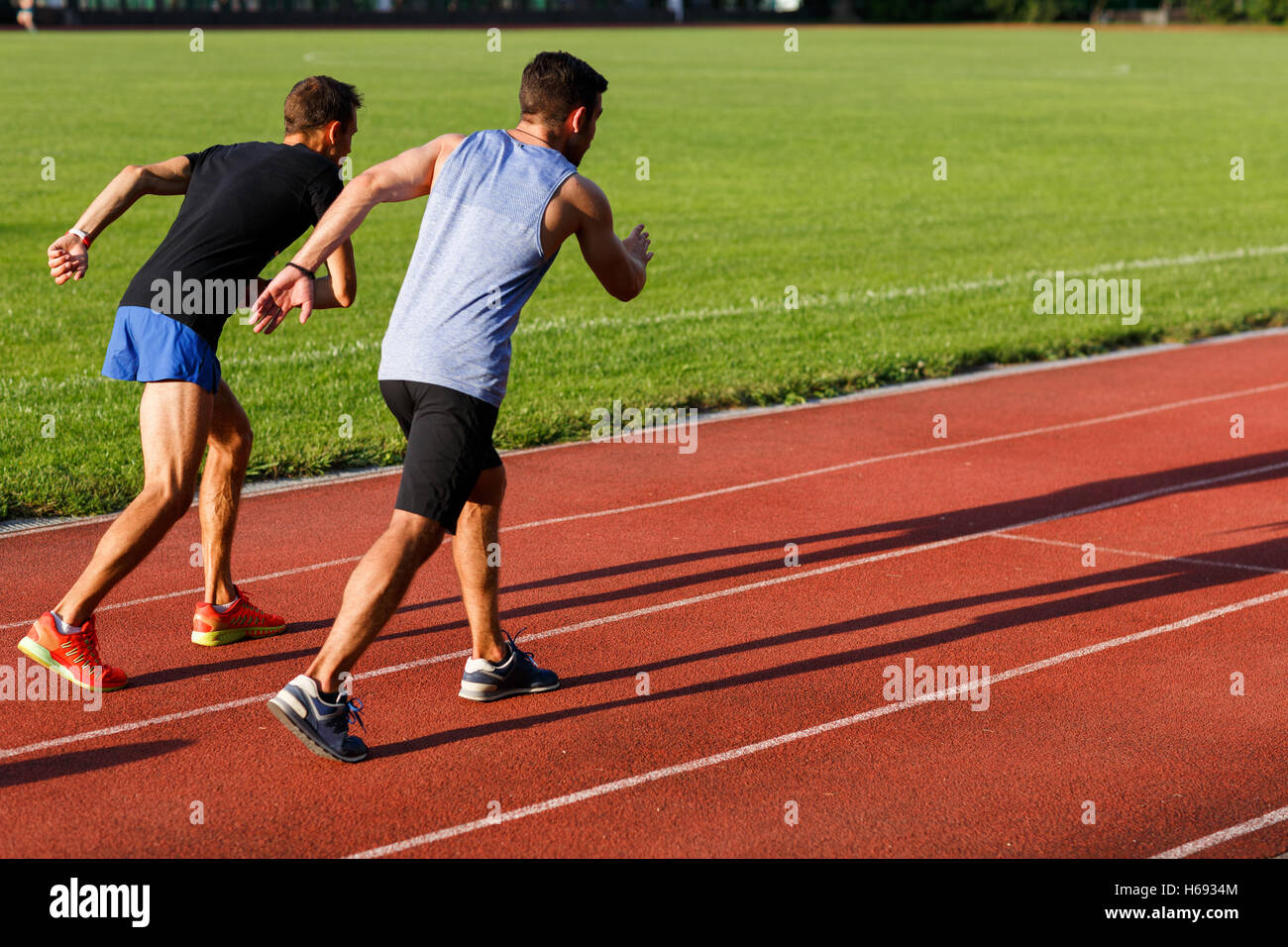 Portrait of two energetic sportsmen running on stadium track Stock ...