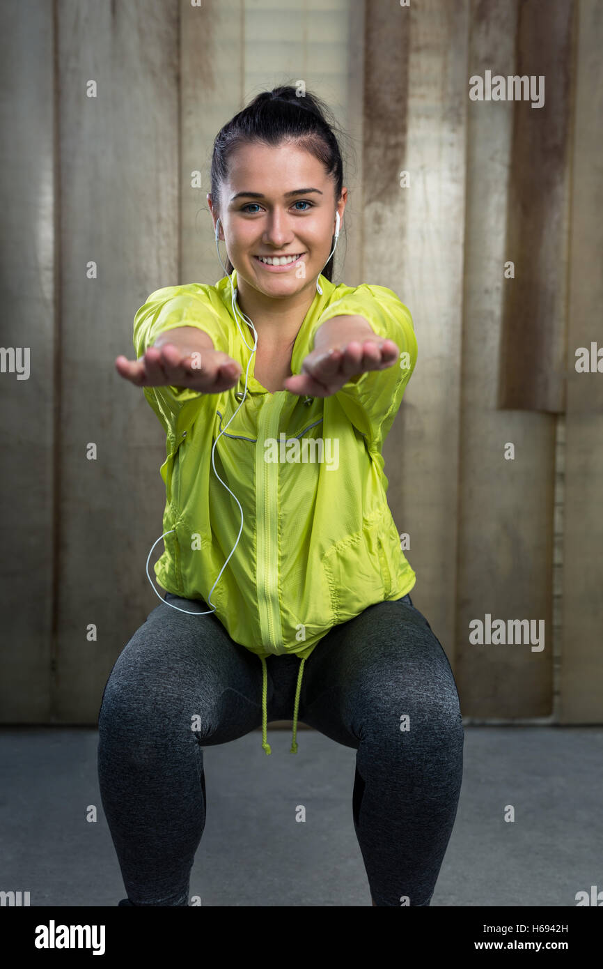 Deep squat. Front view of young beautiful woman in sportswear doing ...