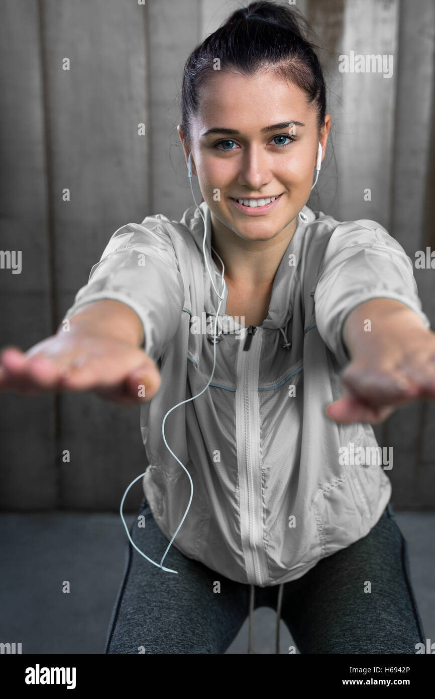 Deep squat. Front view of young beautiful woman in sportswear doing ...