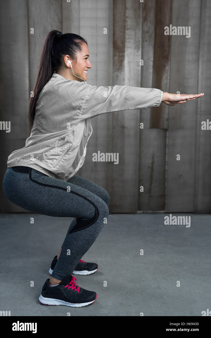 Deep squat. Side view of young beautiful woman in sportswear doing ...