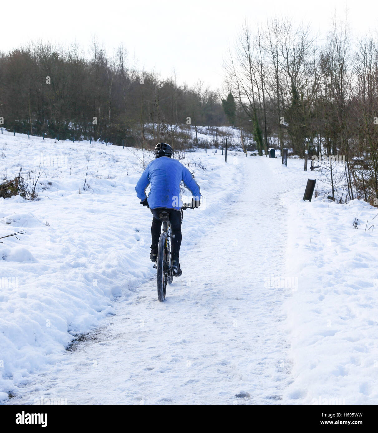 A cyclist riding his bike through the snow in winter on a snow covered ...