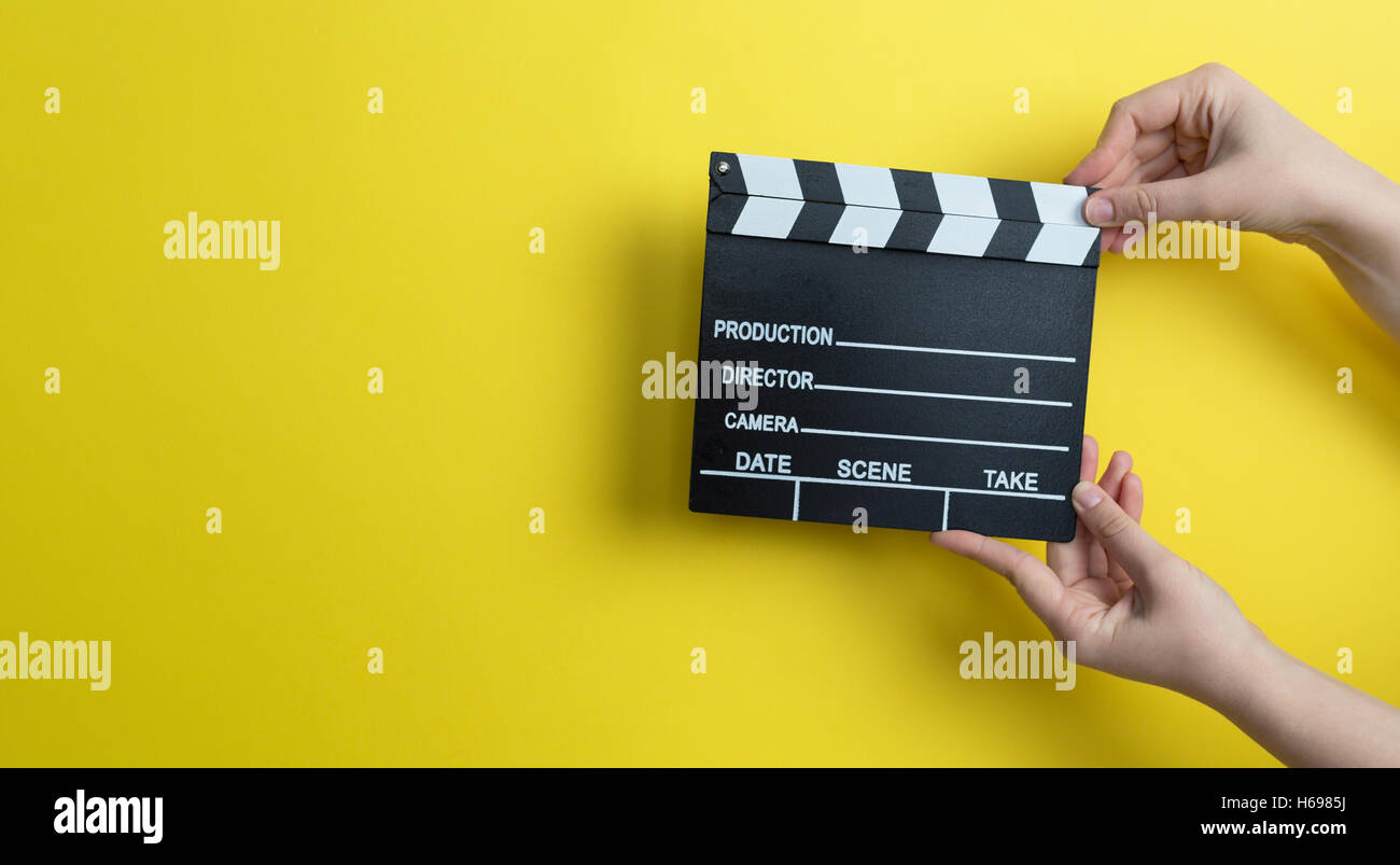 woman holding movie clapper on yellow background, cinema concept Stock ...