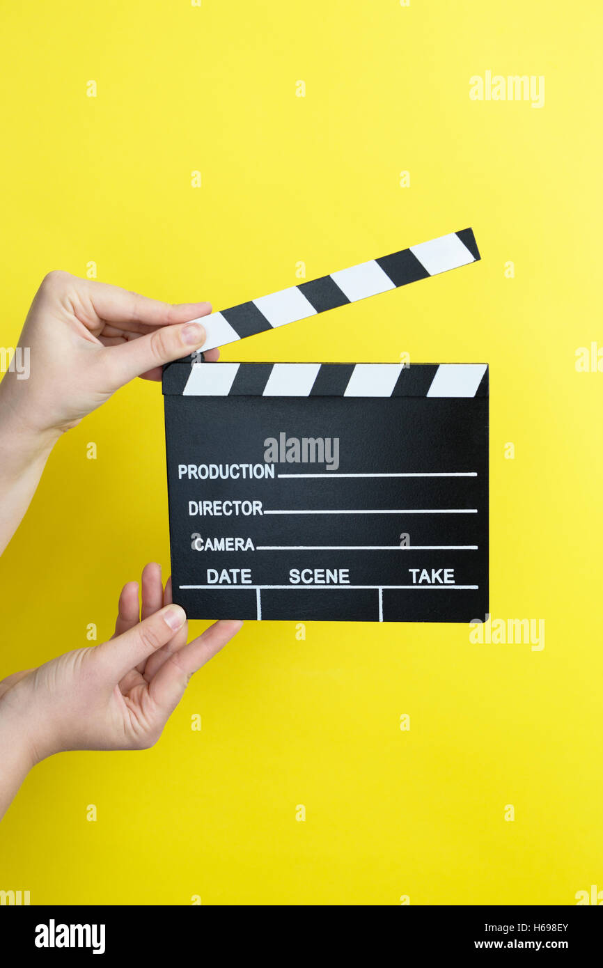 woman holding movie clapper on yellow background, cinema concept Stock ...
