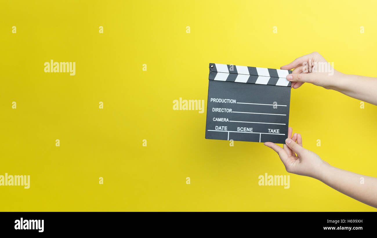woman holding movie clapper on yellow background, cinema concept Stock ...