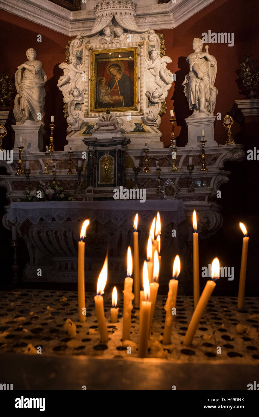 Offering candles are lit in front of an elaborate altar inside the ...