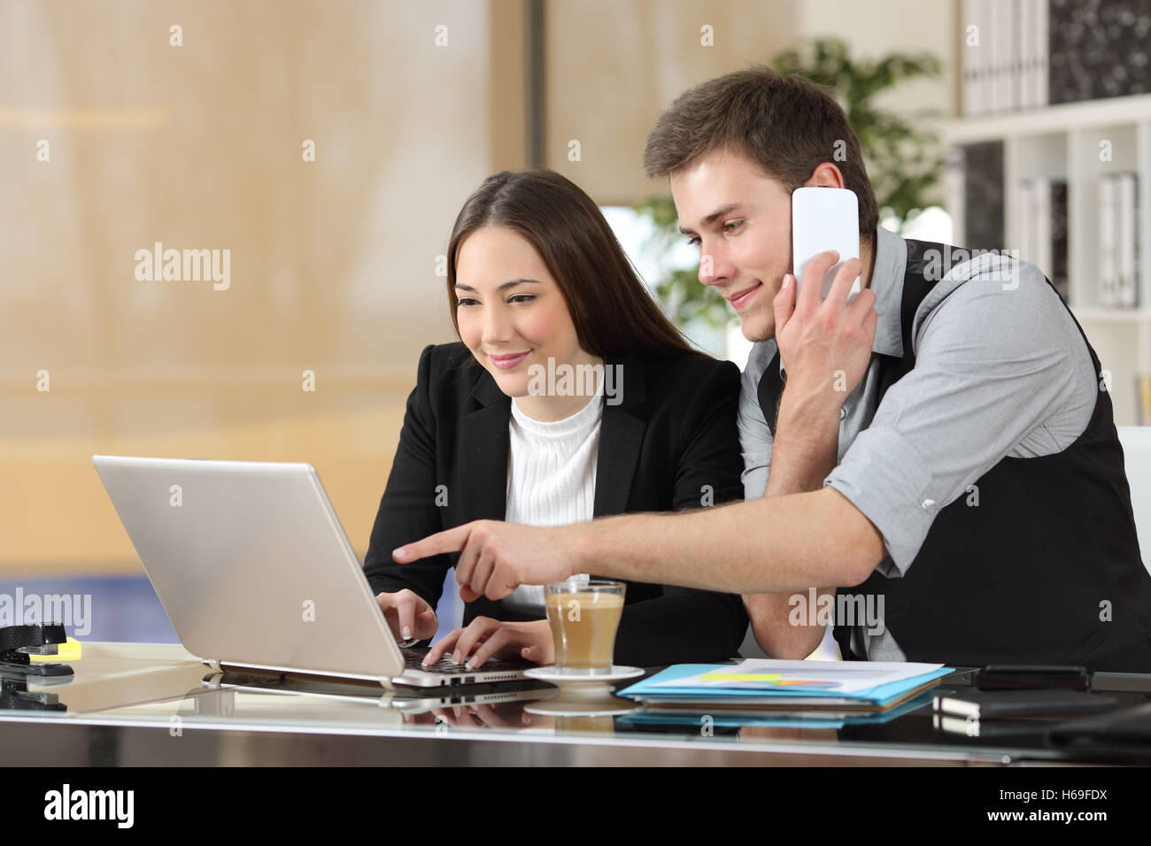 Two coworkers working together online giving instructions with a laptop ...