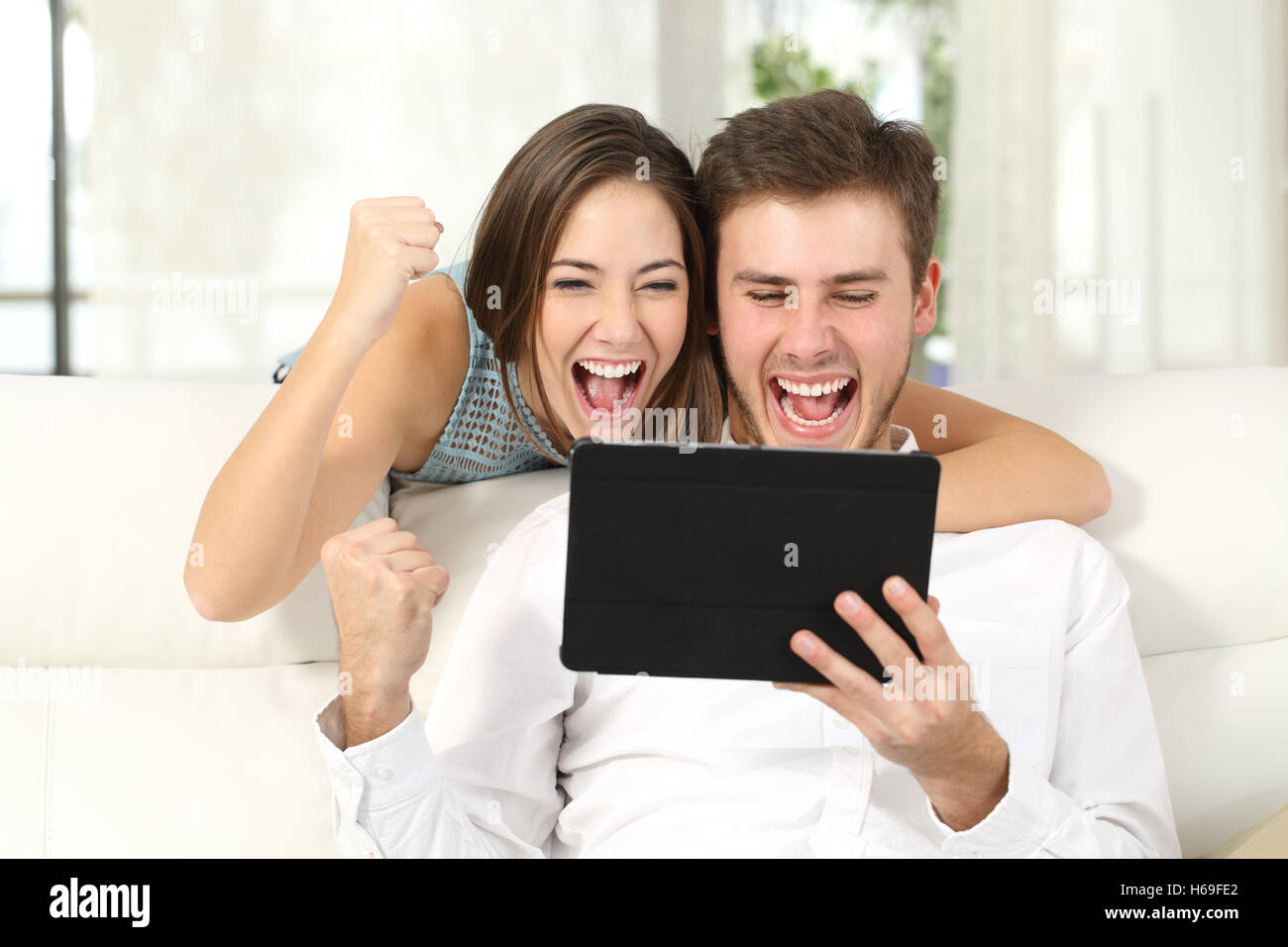 Front view of an excited couple winning online watching content in a ...
