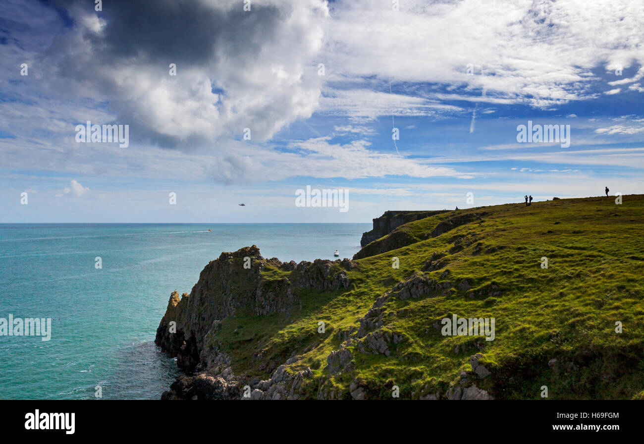 Silhouetted walkers on Stackpole Head on the Pembrokeshire Coastal Path ...