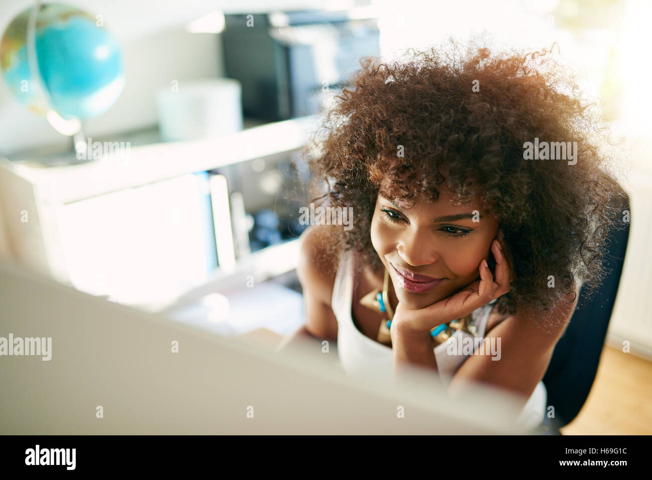 Happy satisfied young businesswoman reading data on her desktop ...