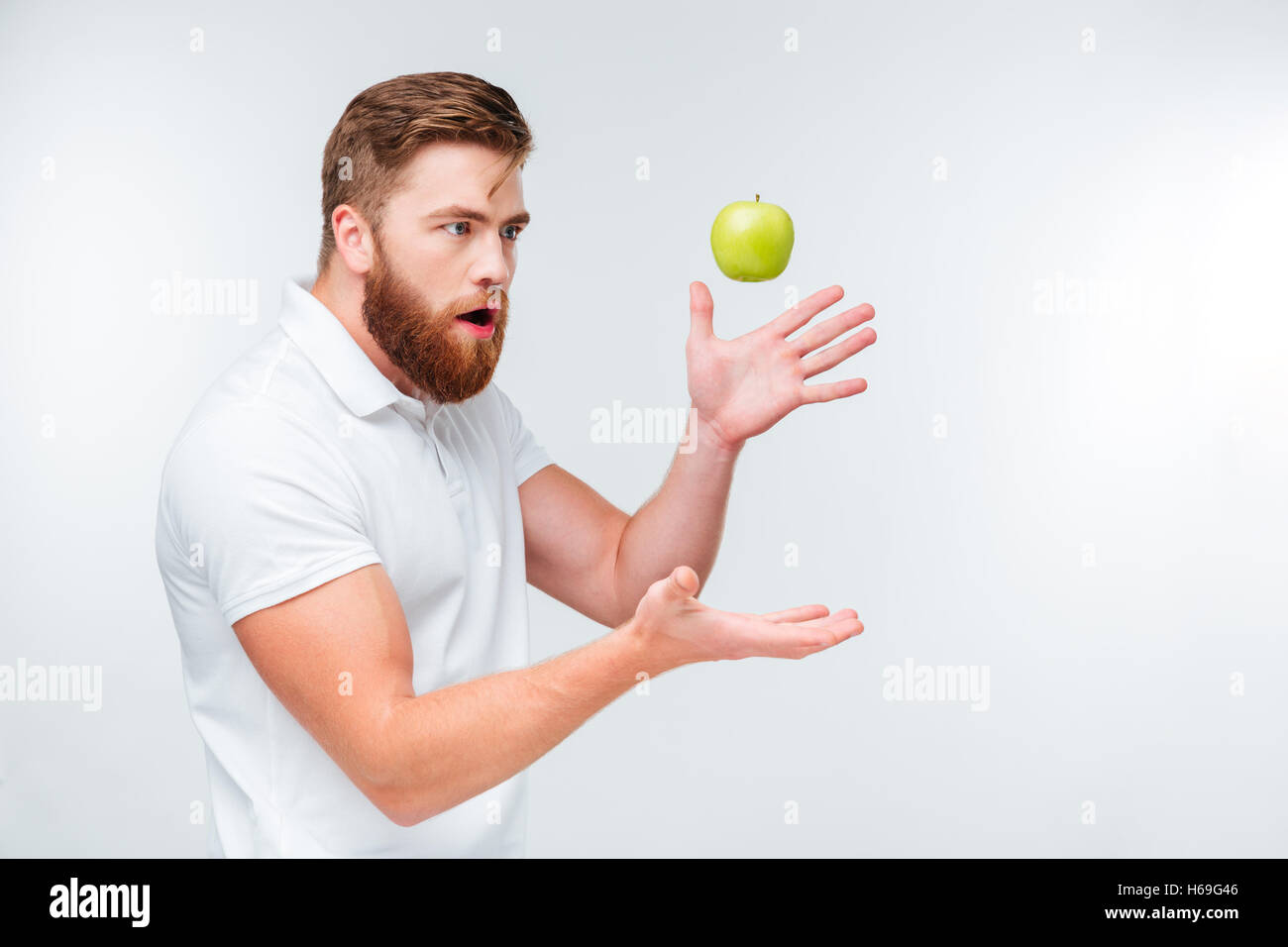 Funny bearded man throwing up a green apple isolated on white ...