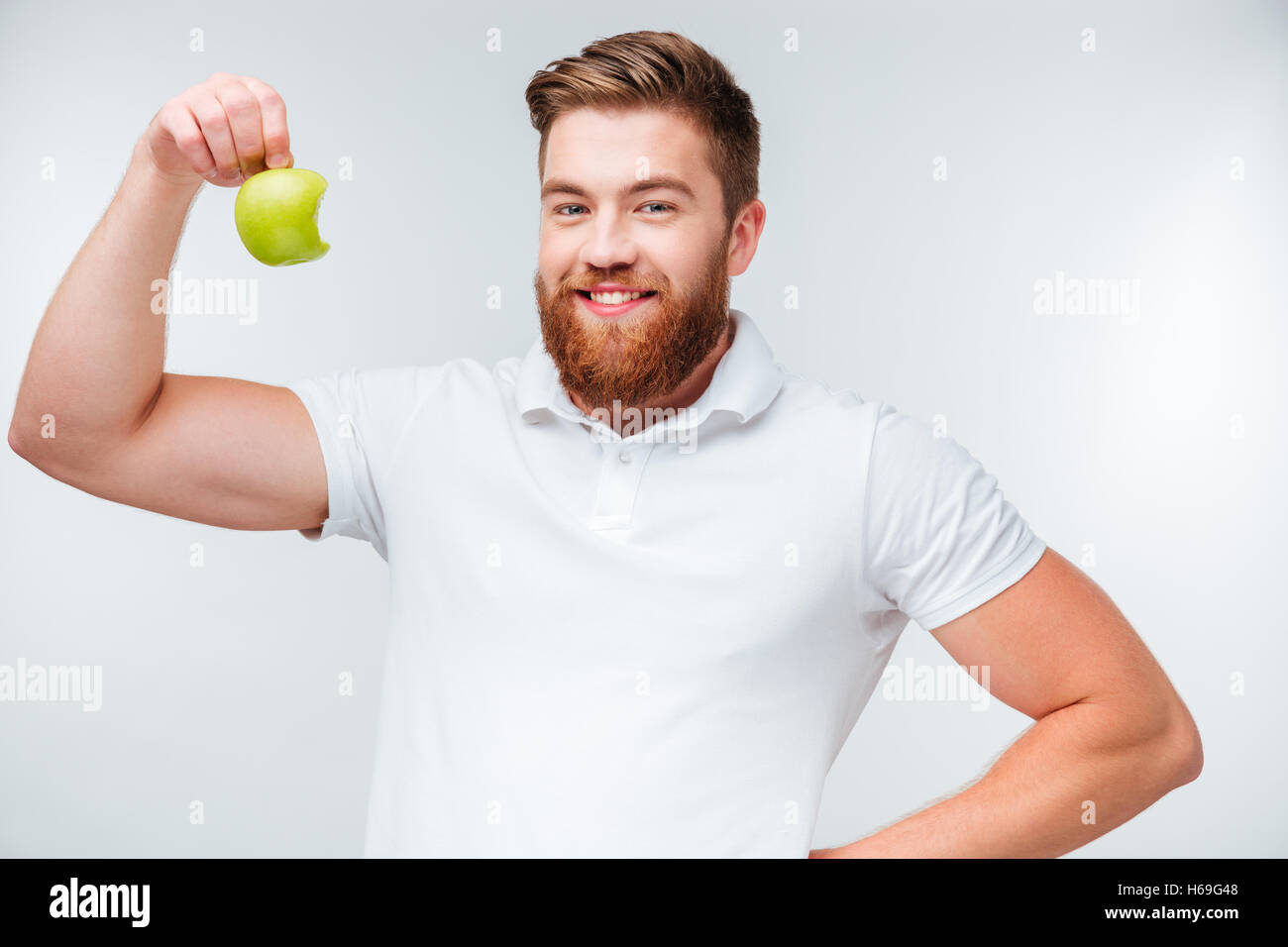 Portrait of a handsome man holding apple and showing biceps isolated on ...