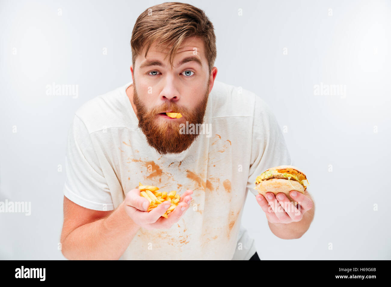 Funny hungry bearded man eating junk food isolated on white background ...