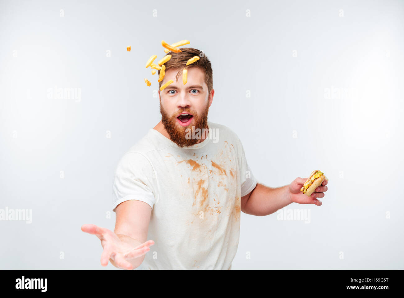 Funny bearded man in dirty shirt throwing french fries isolated on ...