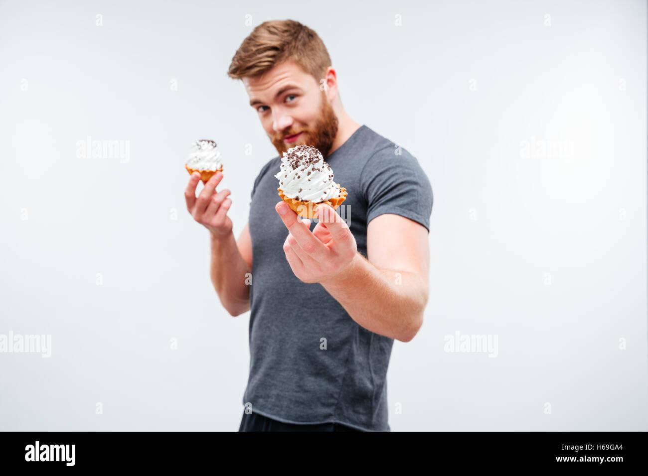 Attractive bearded man showing cream cakes isolated on white background ...