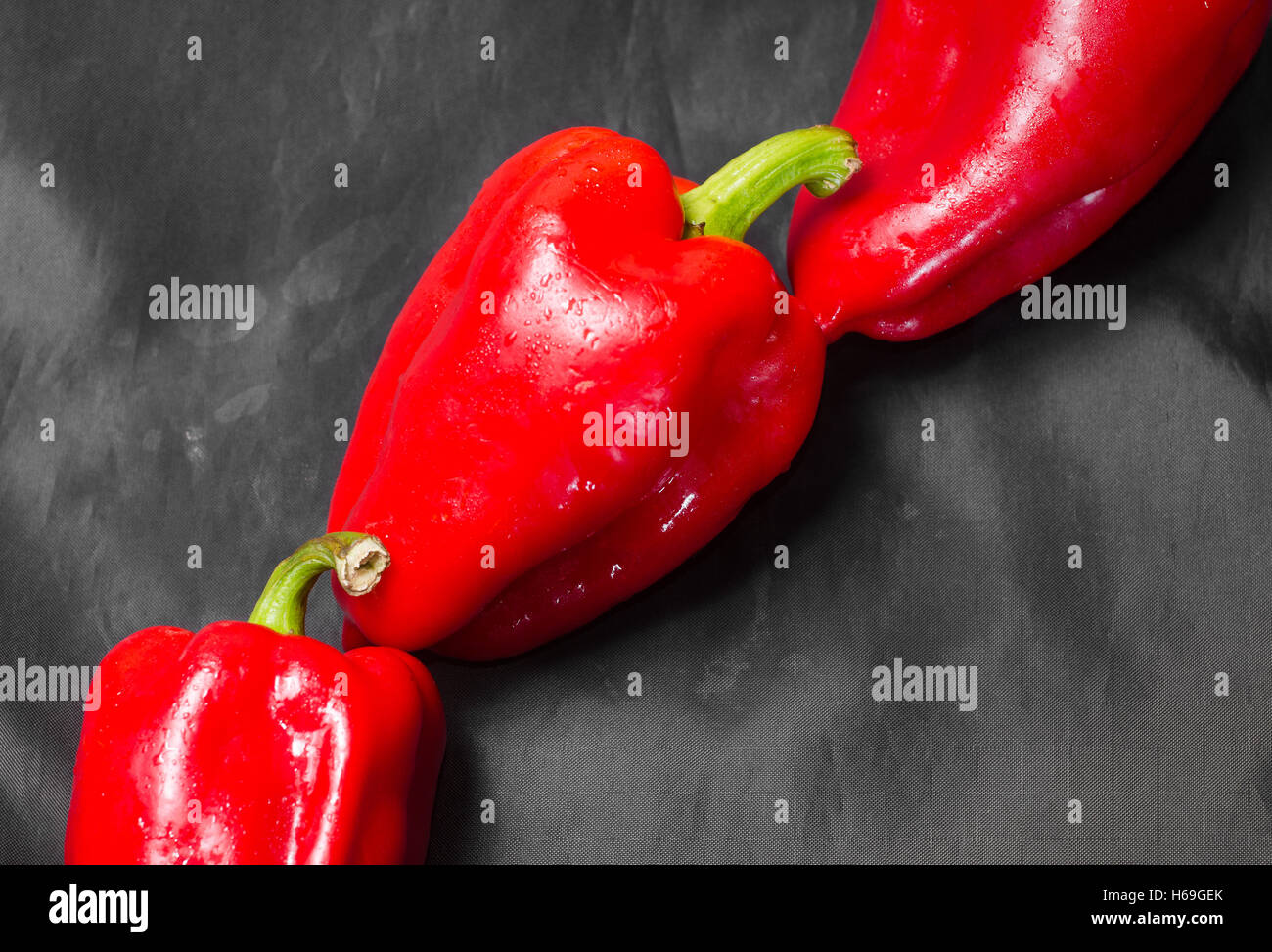 Three red peppers on black background Stock Photo - Alamy