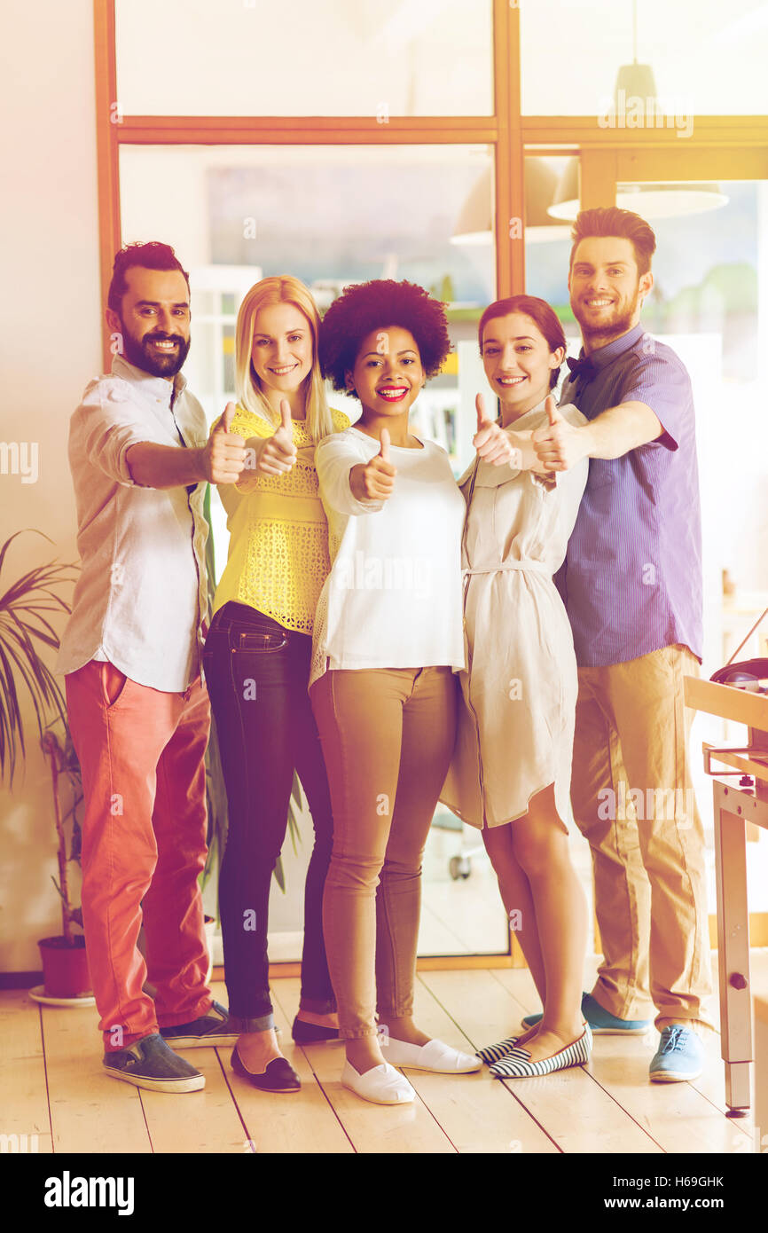happy creative team showing thumbs up in office Stock Photo - Alamy