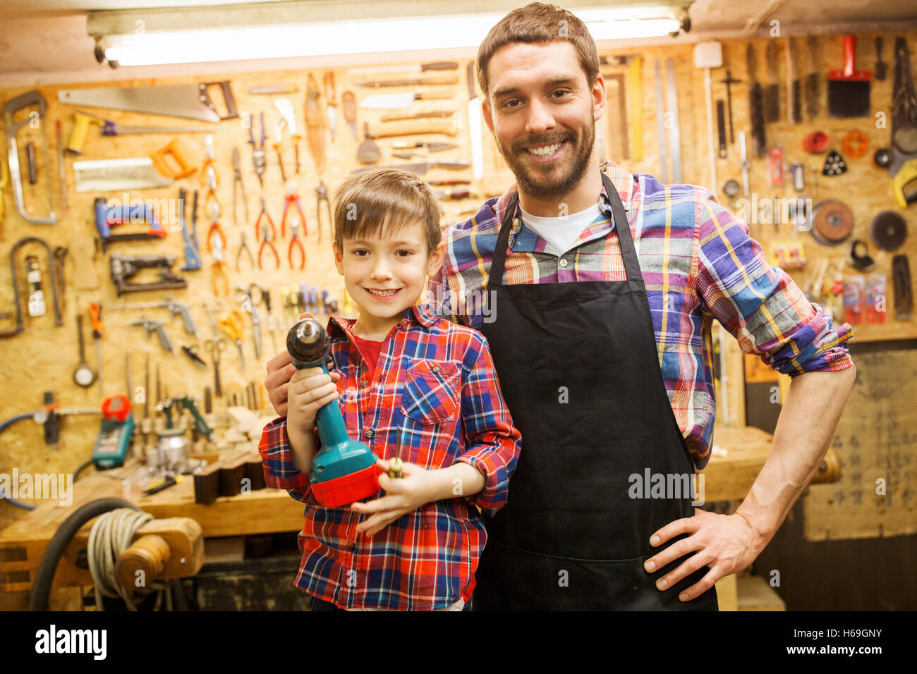 father and son with drill working at workshop Stock Photo - Alamy