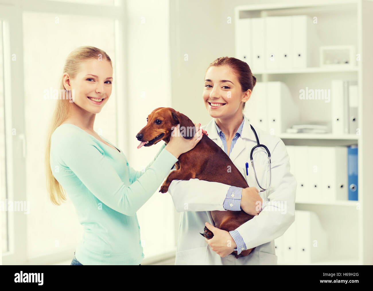 happy woman with dog and doctor at vet clinic Stock Photo - Alamy