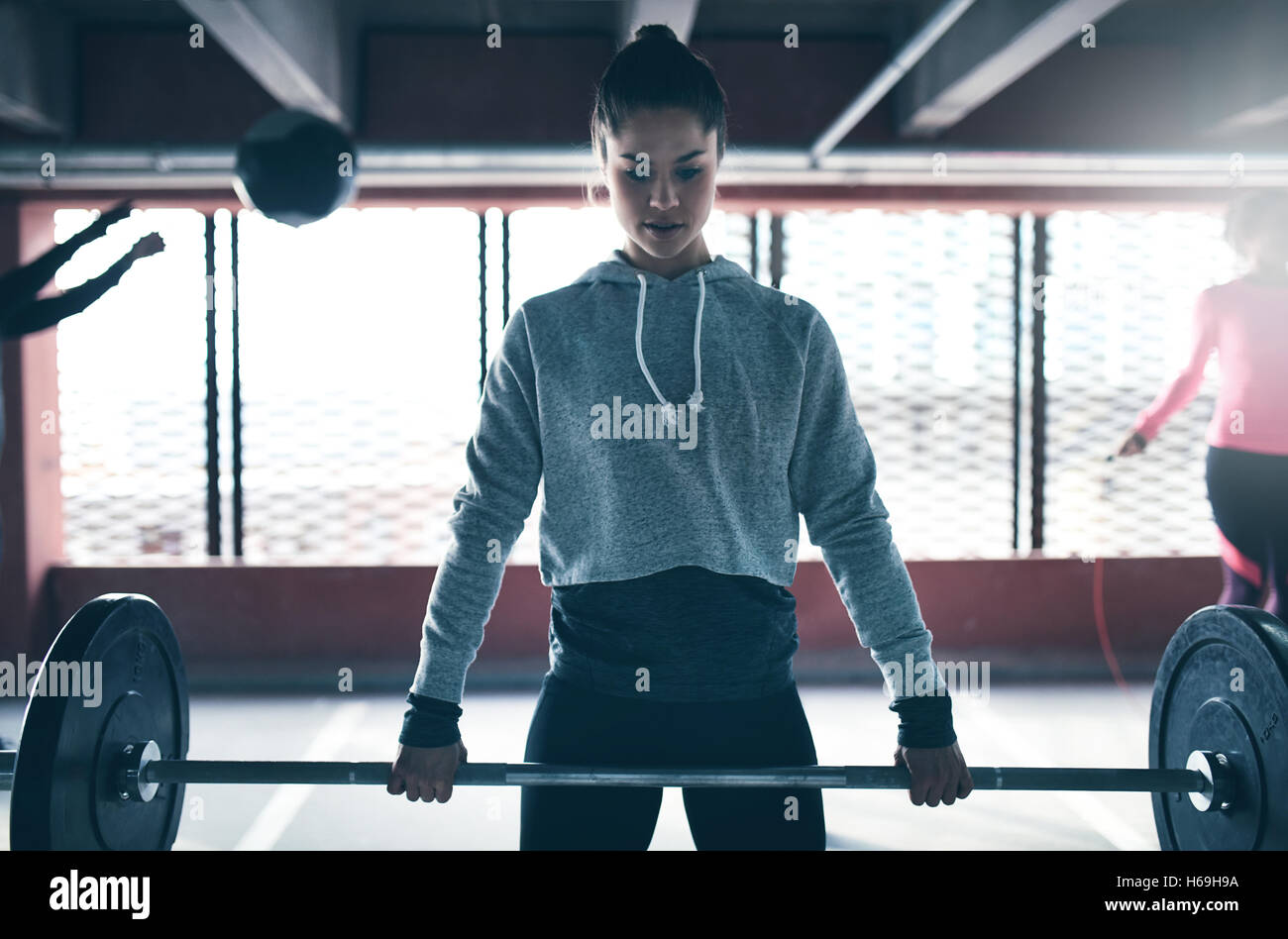 Fit healthy woman lifting a weight barbell, exercising with group of ...