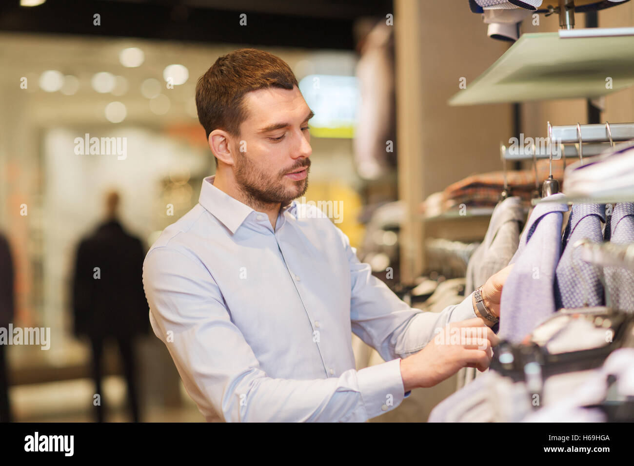 happy young man choosing clothes in clothing store Stock Photo - Alamy
