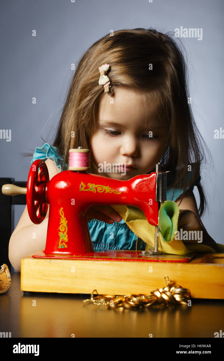little girl is playing with sewing machine Stock Photo - Alamy