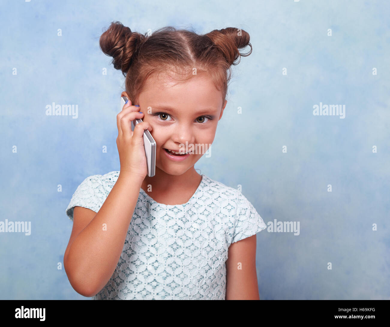 Funny kid girl talking on mobile phone with happy smile on blue ...