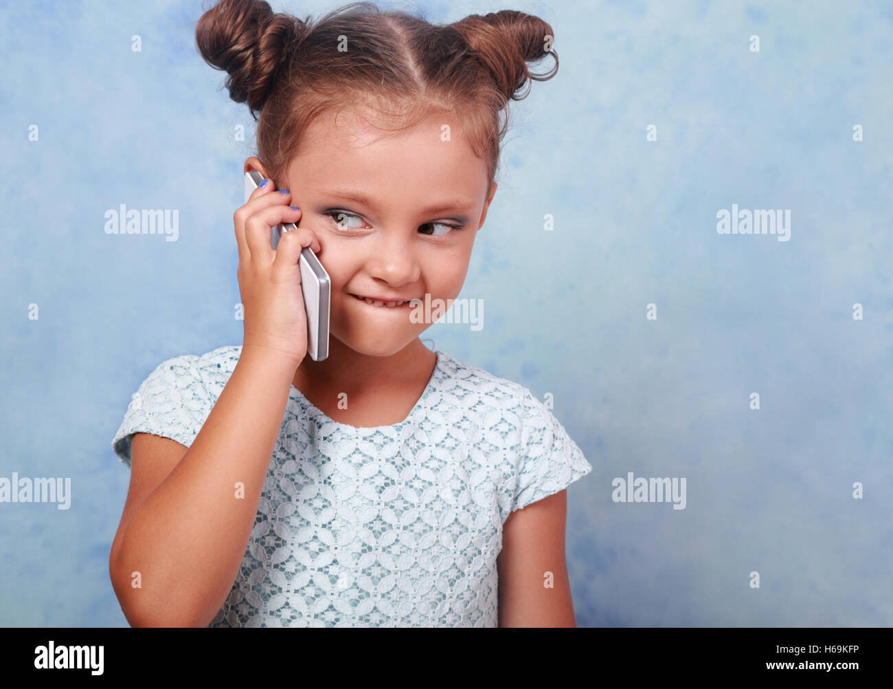 Funny kid girl talking on mobile phone with happy smile on blue ...