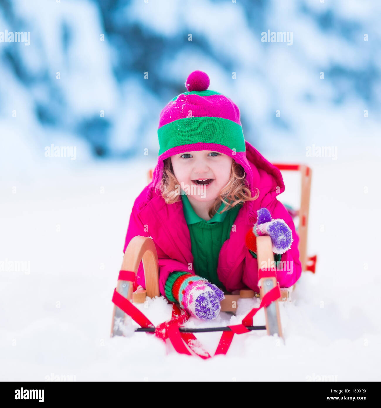 Little girl enjoying a sleigh ride. Child sledding. Toddler kid riding ...