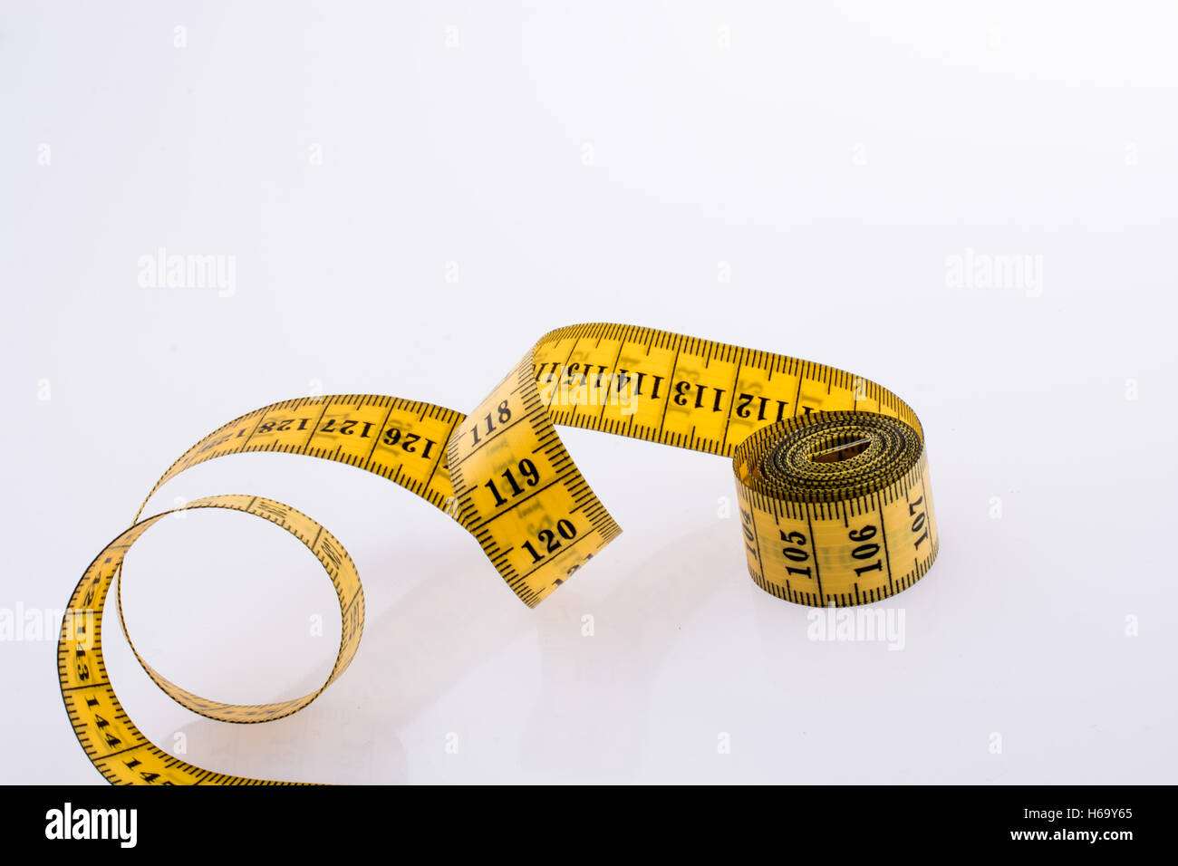 Yellow color measuring tape on a white background Stock Photo - Alamy