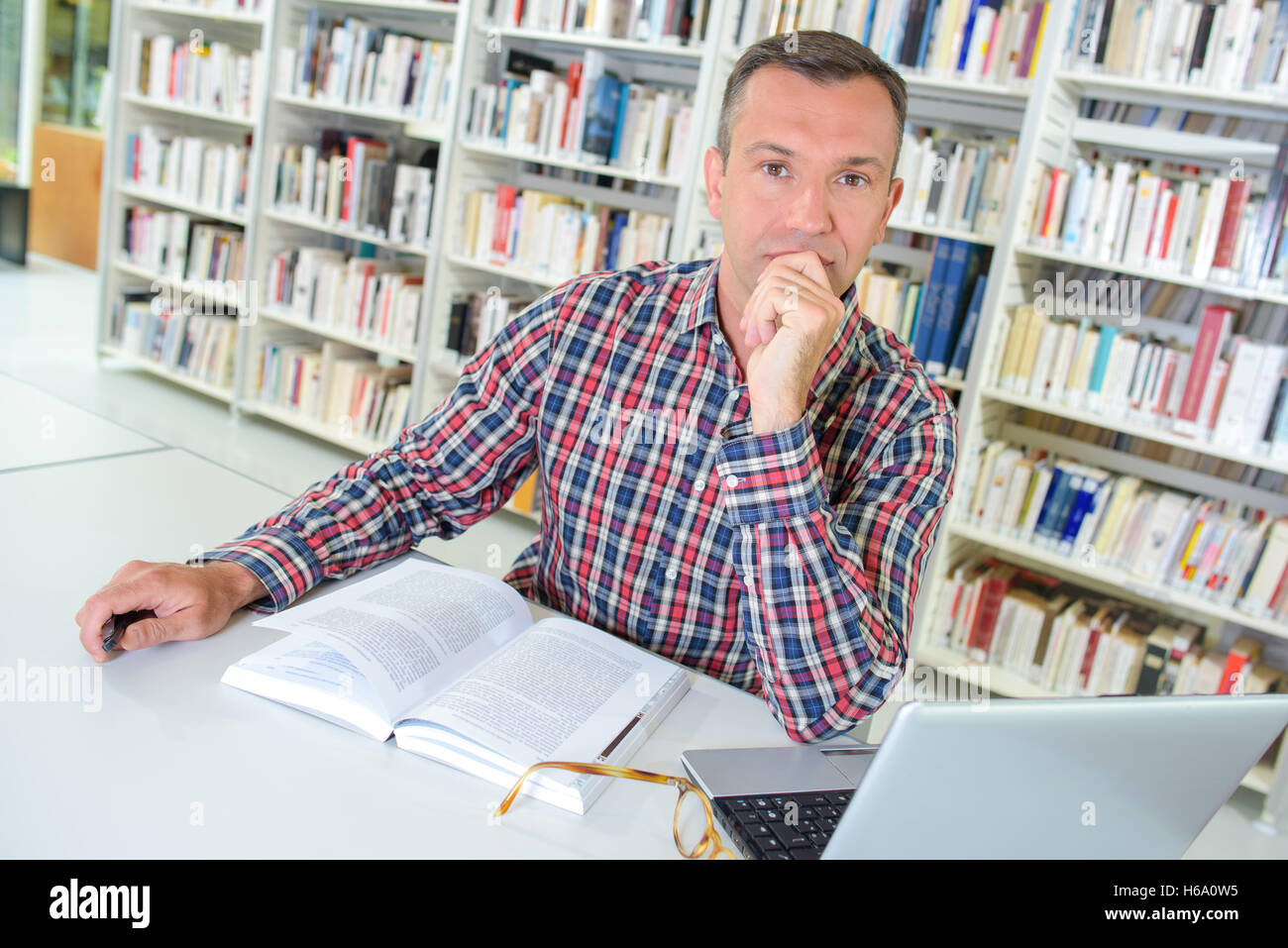 Contemplative man in library Stock Photo - Alamy