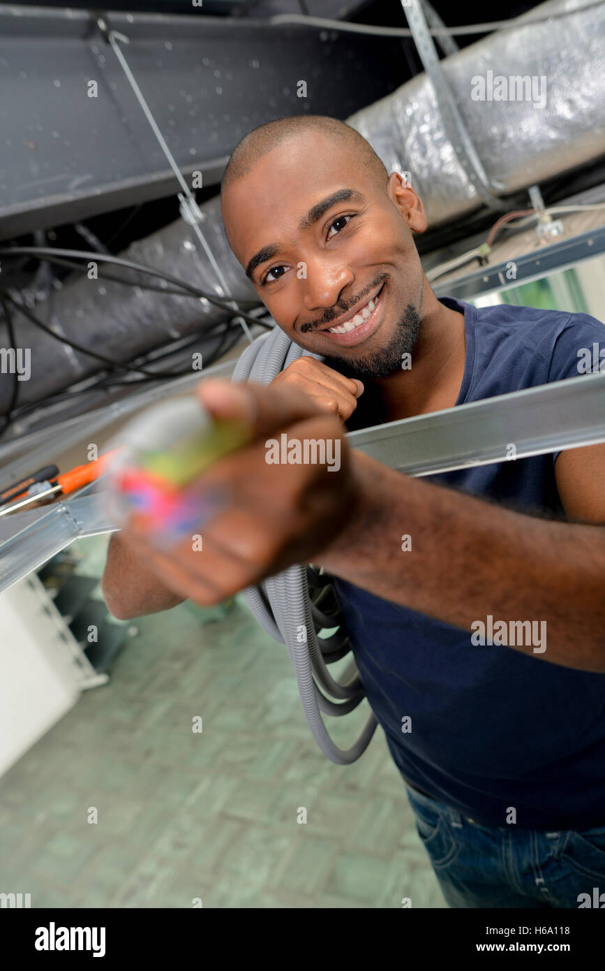 Man in roof space, holding cable forward Stock Photo - Alamy