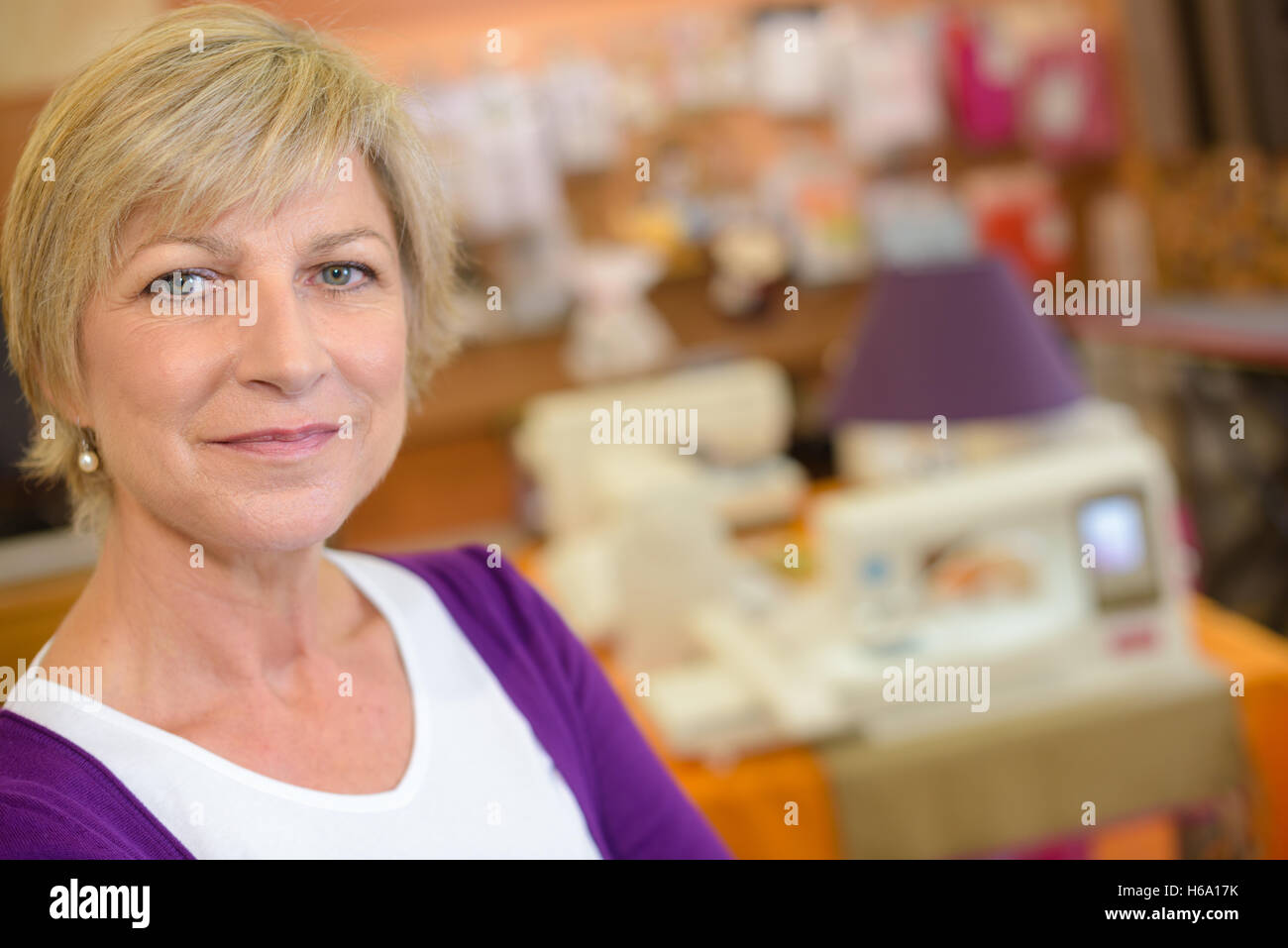 Portrait of mature woman, sewing machine in background Stock Photo - Alamy