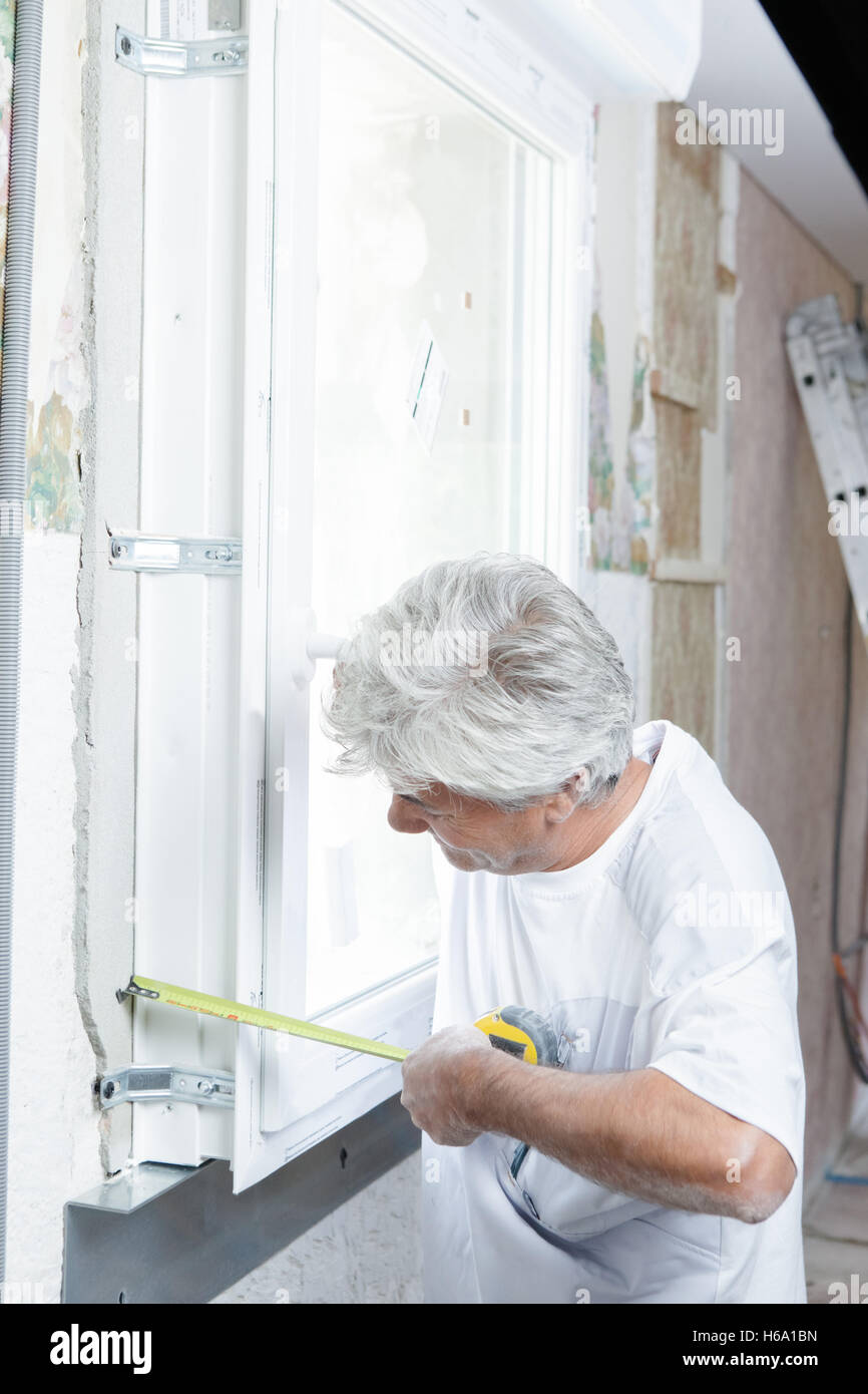 Mason measuring up a window Stock Photo - Alamy