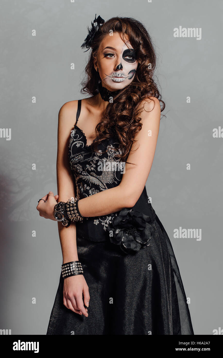 Young woman in black with half face skull make-up Stock Photo - Alamy